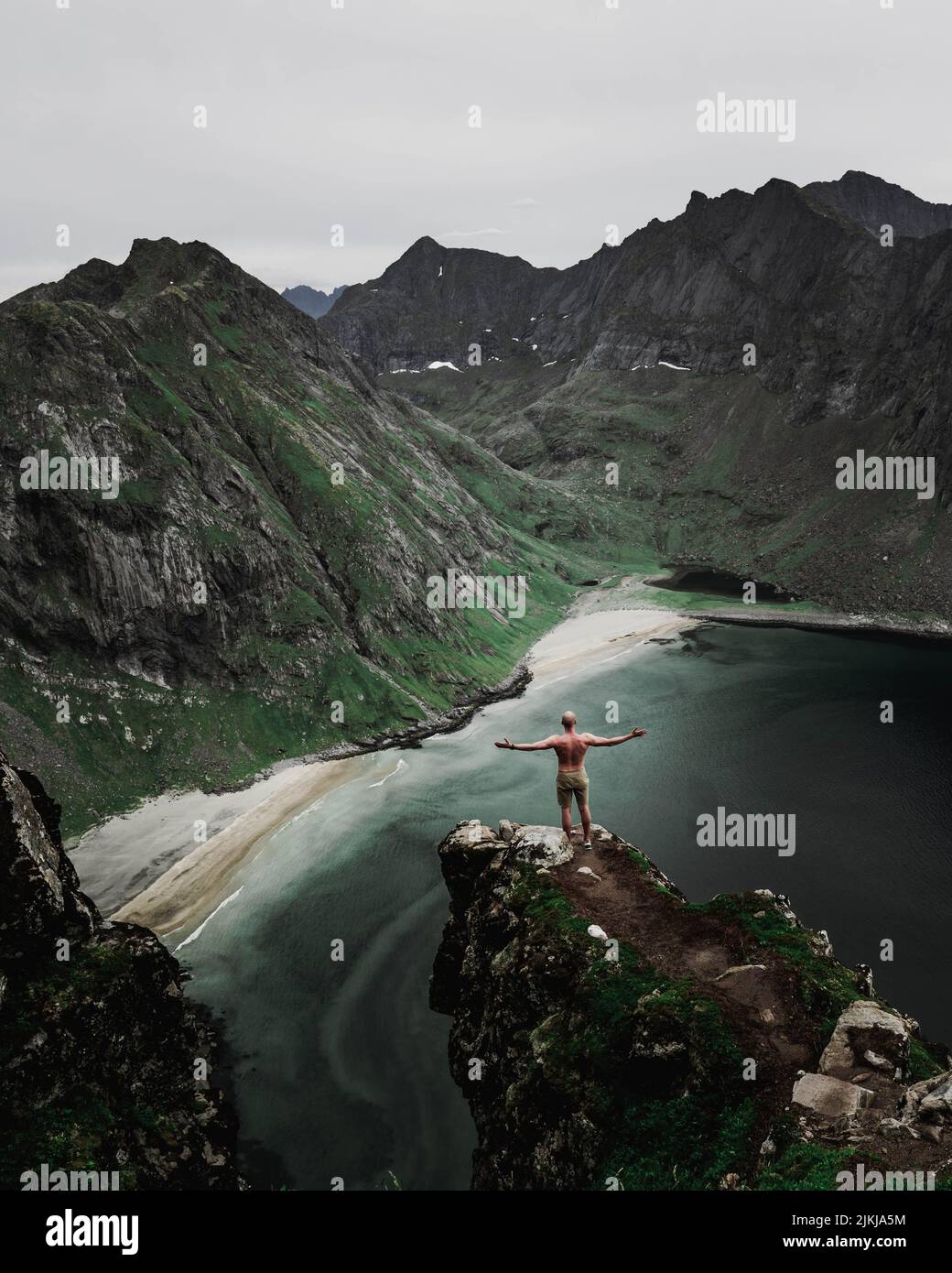 A aerial shot of a man standing on the edge of a cliff overlooking a ...