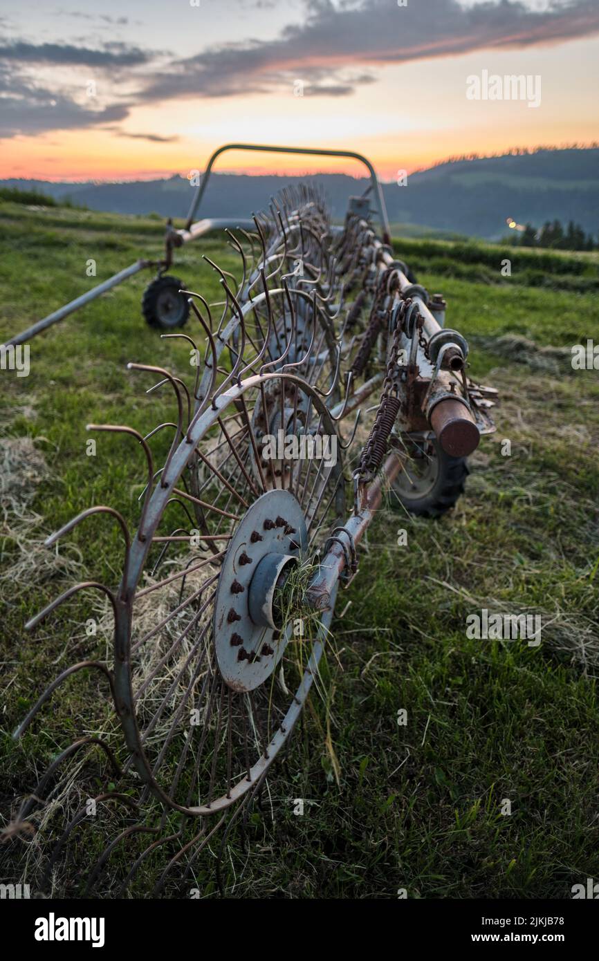 A vertical shot of a rake tedder on wheels for haymaking in a field at ...