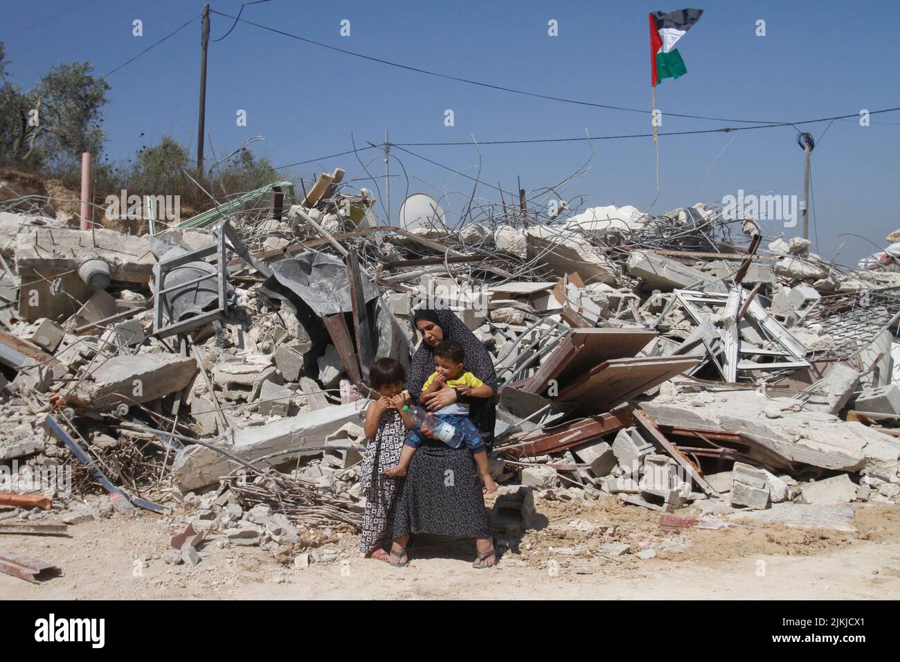 A Palestinian family sits on the rubble of their house after the ...