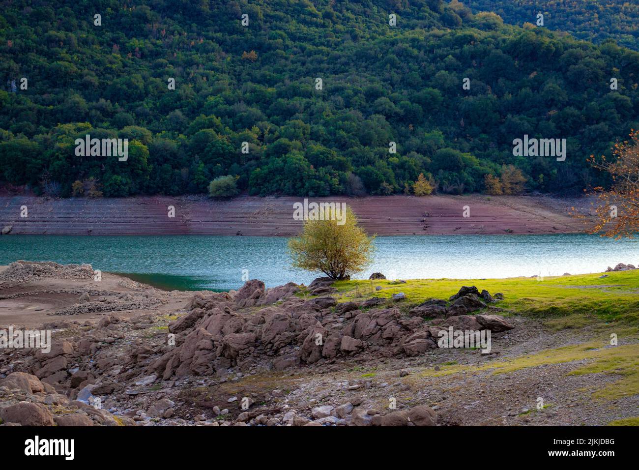 A natural landscape view of a small lake at the feet of a hill with ...