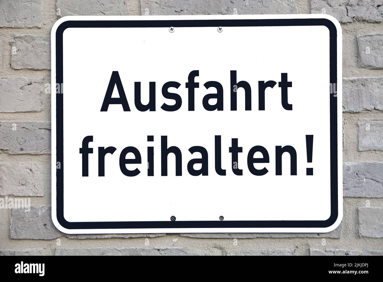 A white sign on a brick wall with the words "Ausfahrt freihalten ...