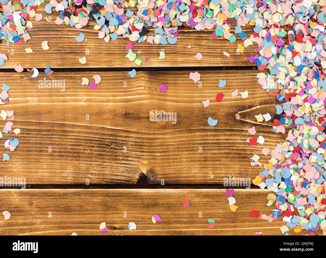 A top view of multicolored confetti and streamers on a wooden table ...