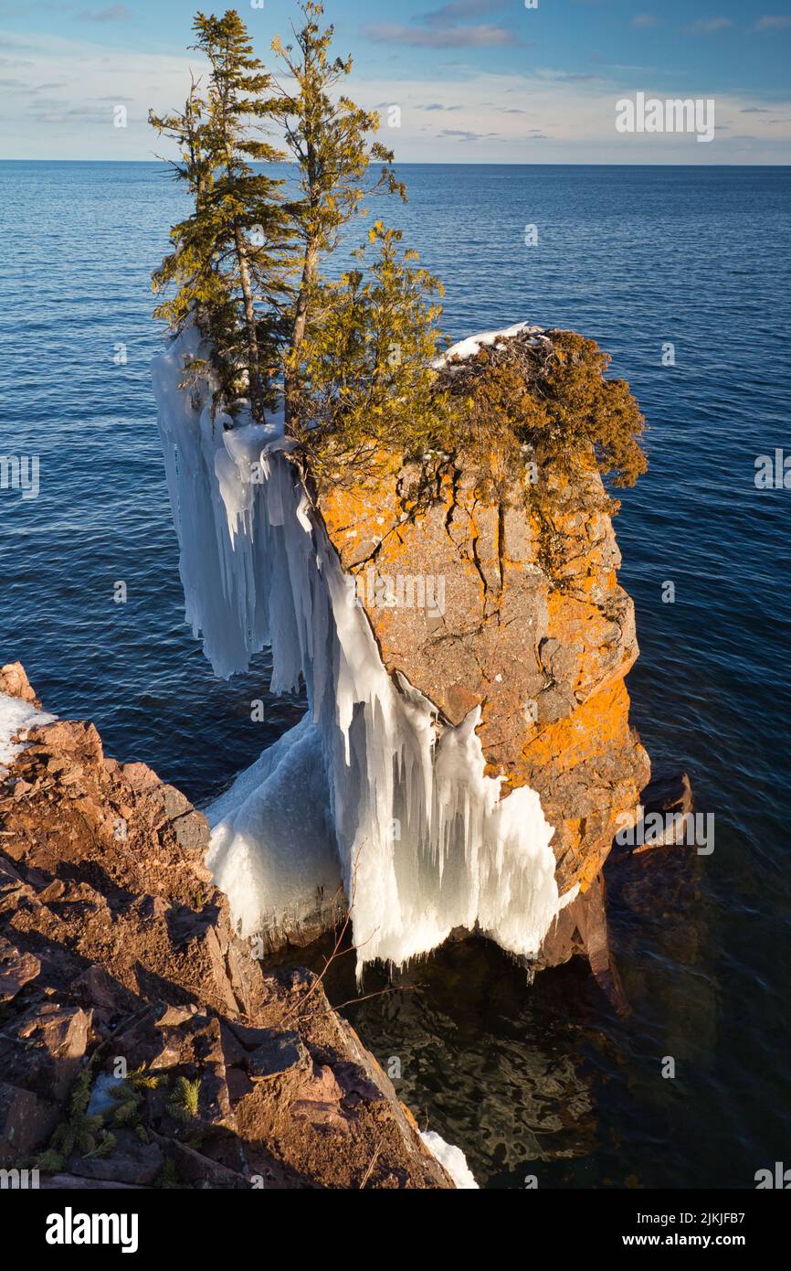 A vertical shot of a parted piece of cliff half-covered with ice, Lake ...