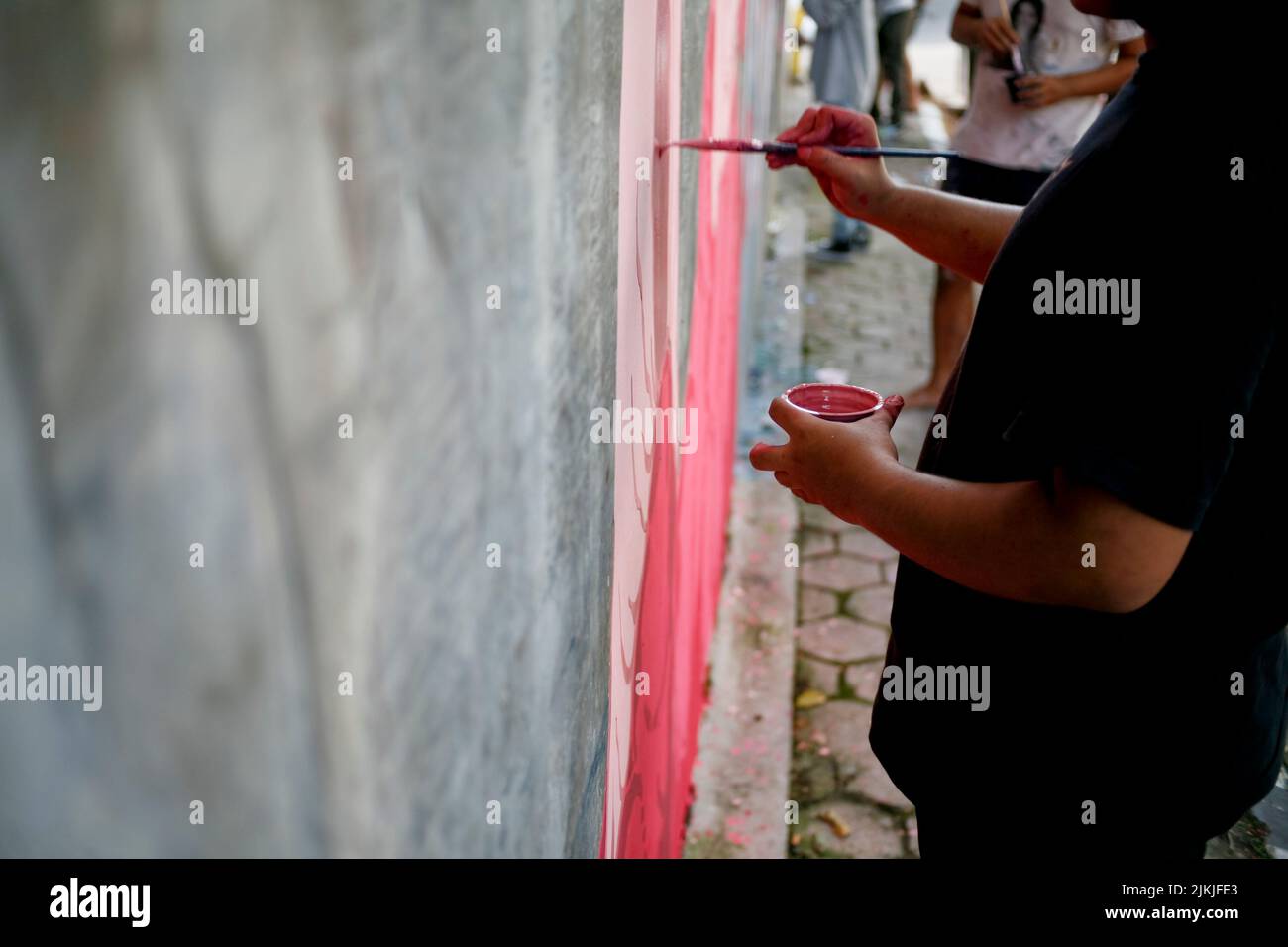 Hand of mural artist paint on the street wall Stock Photo - Alamy