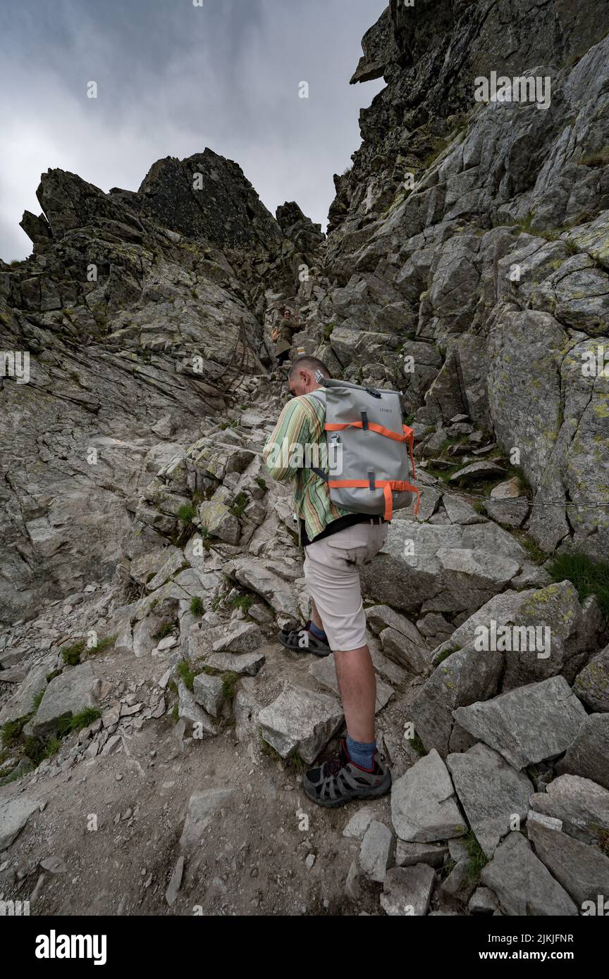 A back view of a male tourist with a backpack hiking in the High Tatras ...