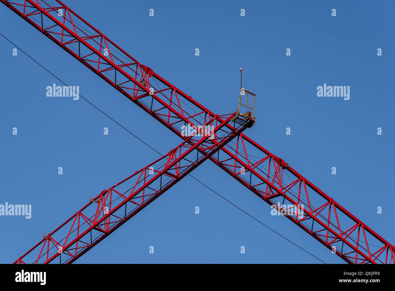 A low angle shot of a big, red construction crane against a blue sky ...