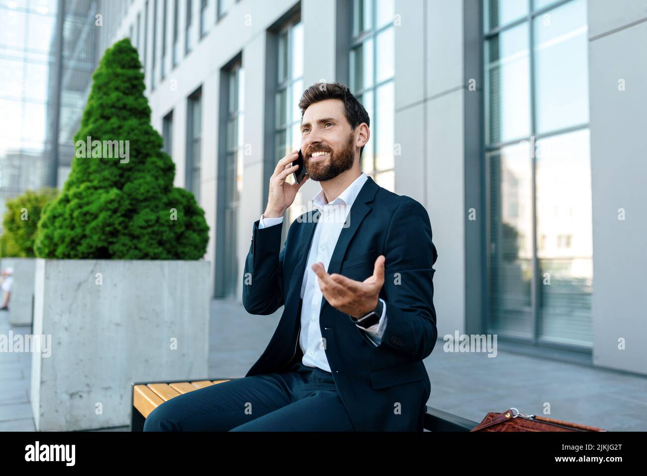 Happy millennial attractive european man with beard in suit calling by ...
