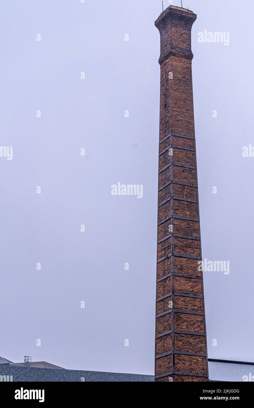 A vertical shot of a tall chimney tower made of red brick rising to the ...