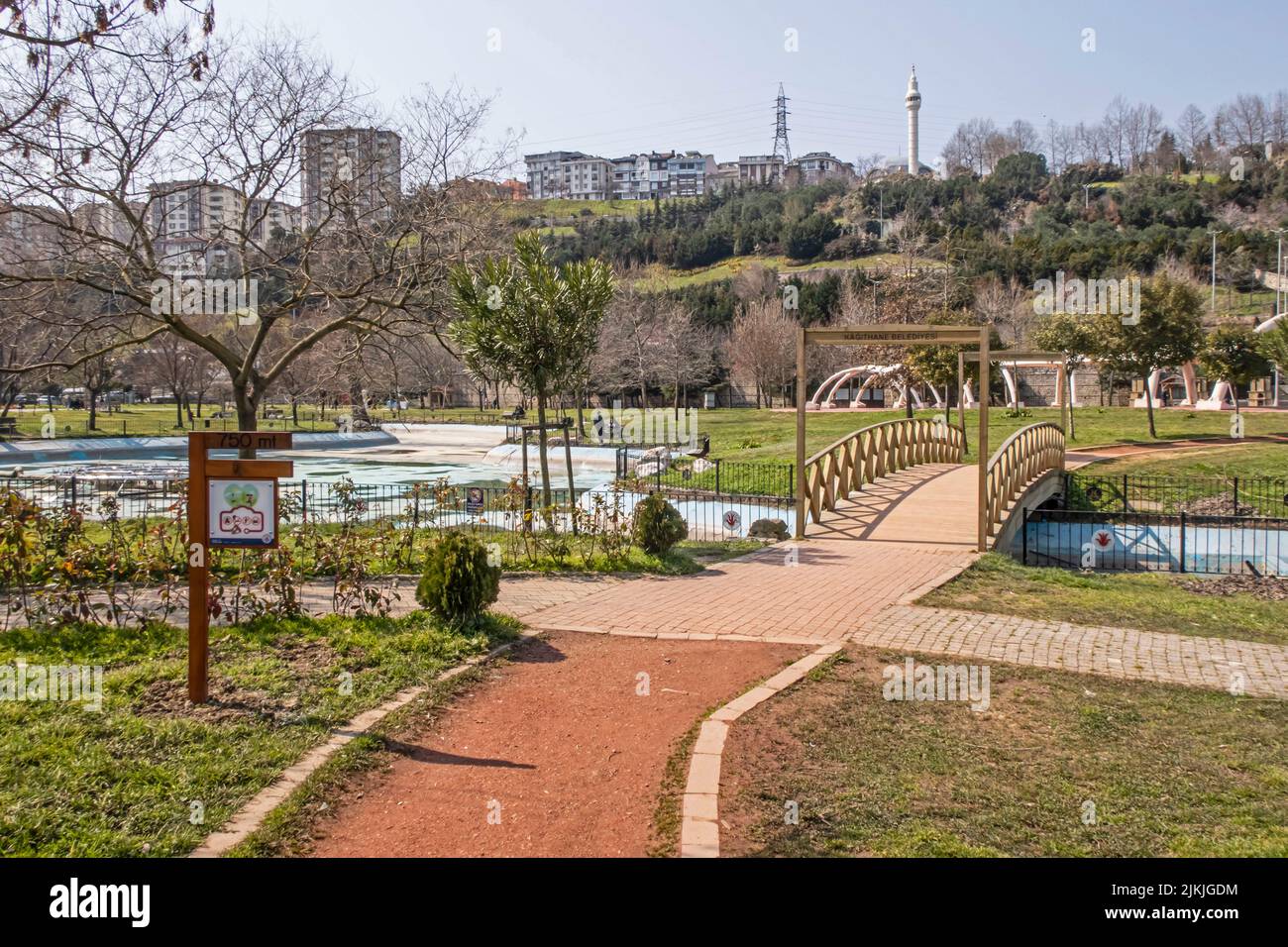 A park with green grass and trees and pool with buildings in a clear ...