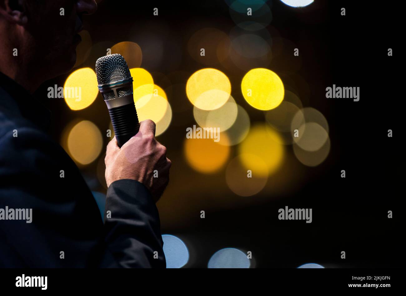 A singer holds a microphone during his concert with bokeh lights in the ...