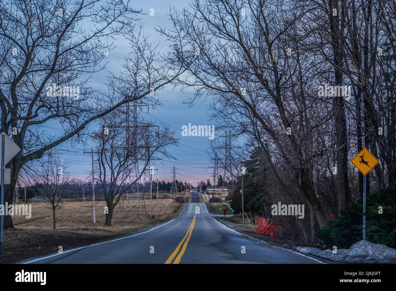 A view of an empty road stretching through fields in early spring with ...