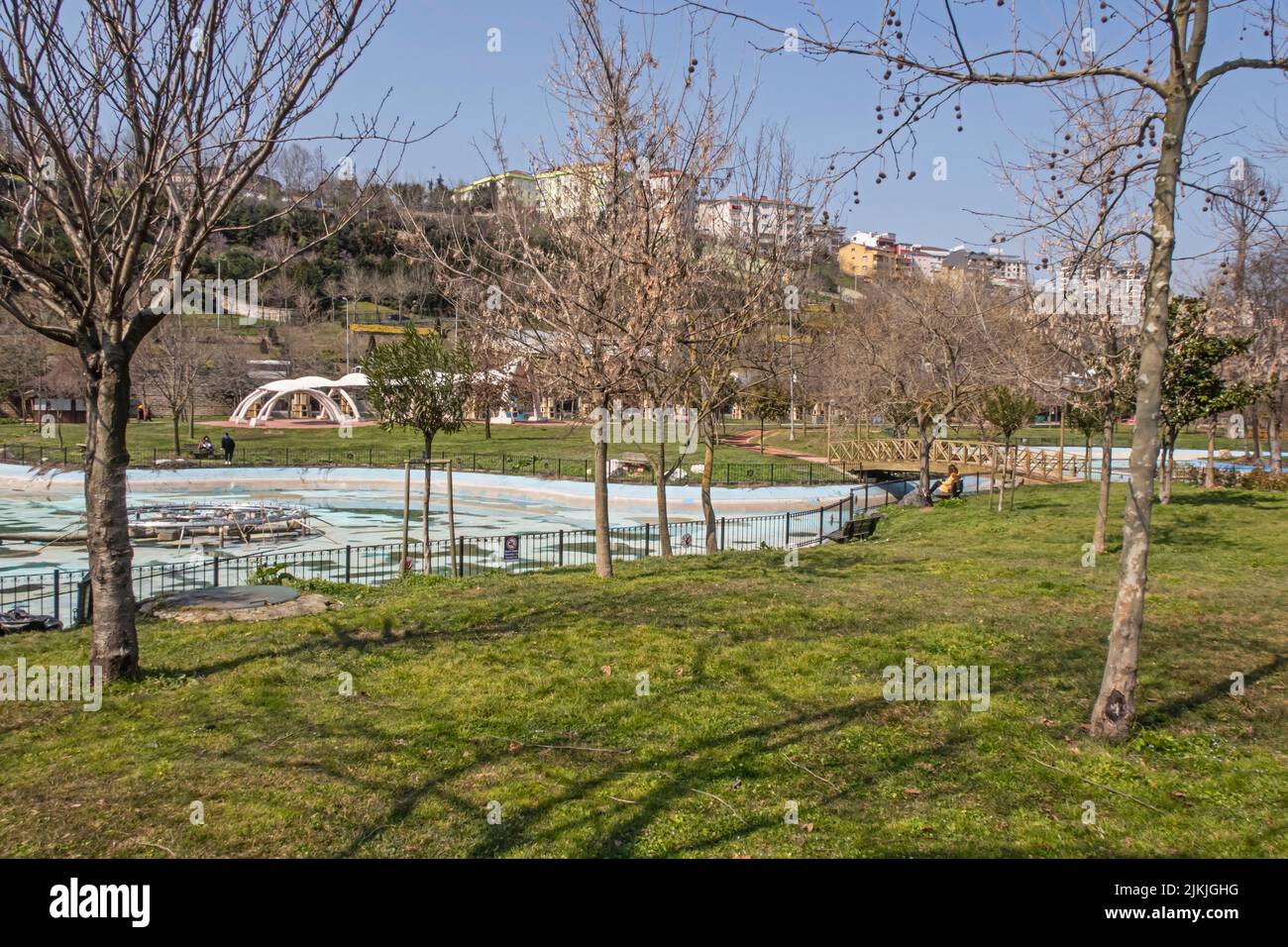 A park with green grass and trees with buildings in a clear sky in the ...