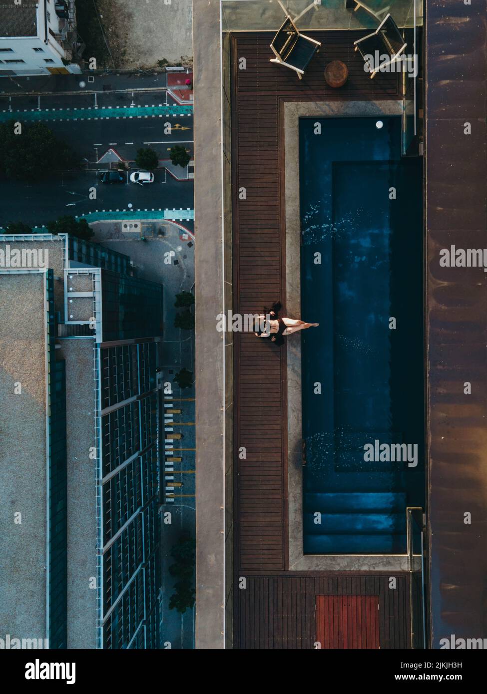 An aerial view of a rooftop pool with a person sitting by the pool ...