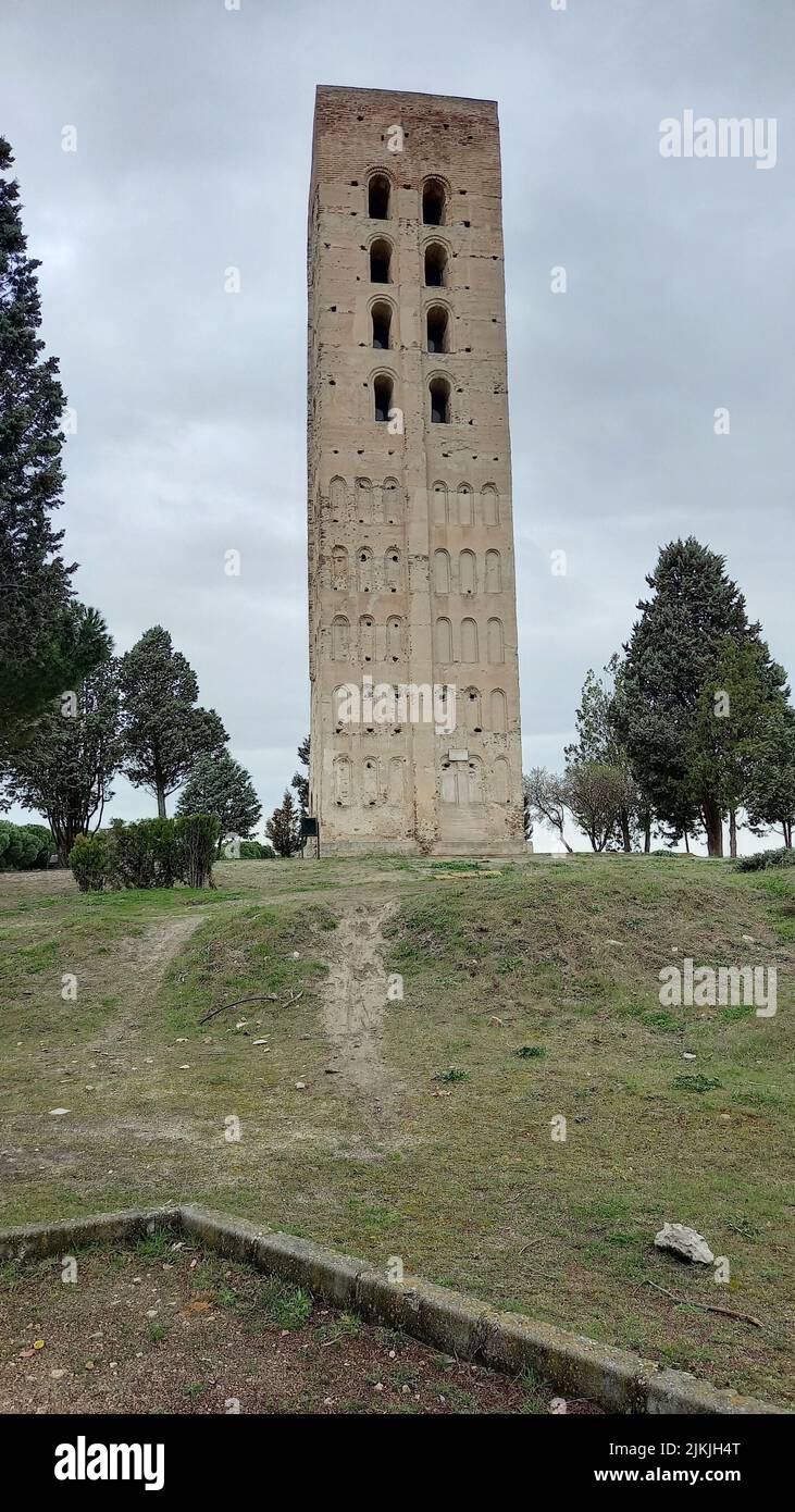 A vertical shot of Torre De San Nicolas tower with trees and cloudy sky ...