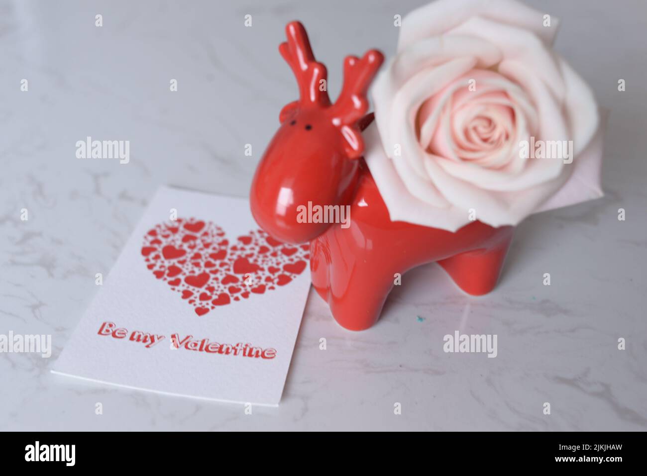 A cute red deer vase with a white rose Stock Photo - Alamy