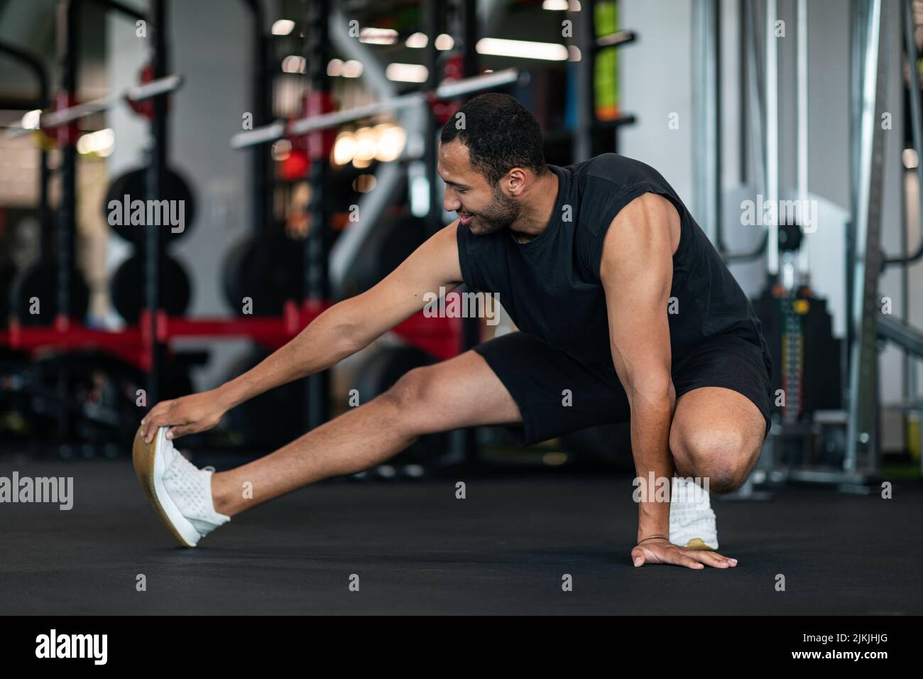 Sporty Young Black Man Stretching Leg Muscles While Training At Gym ...