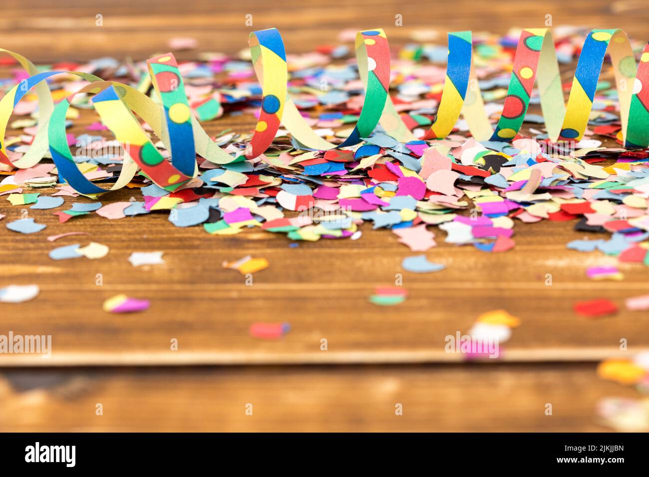 Many colorful confetti and streamer on a blurred wooden background ...