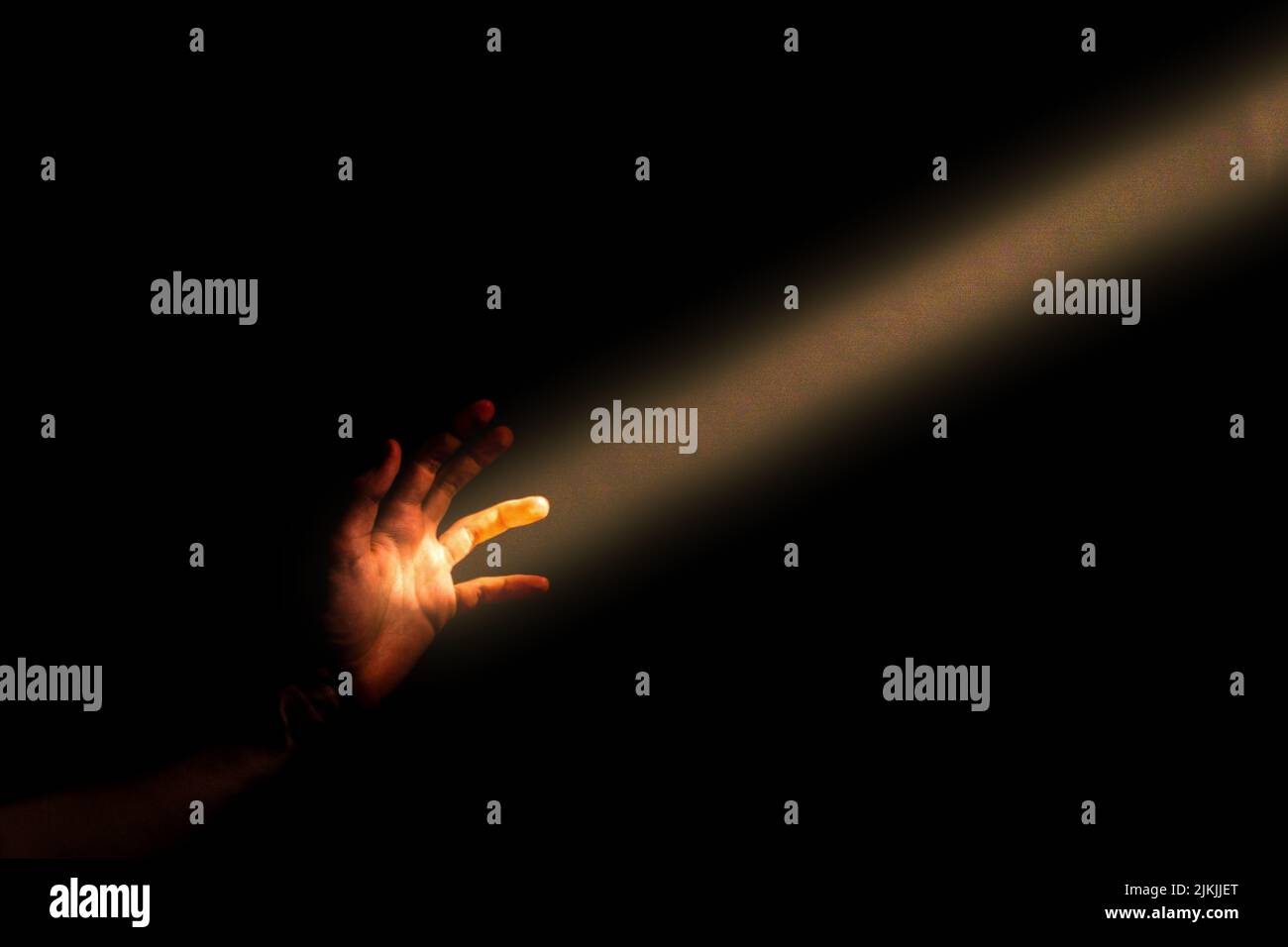 A hand reaching out for a beam of light on a black background Stock ...