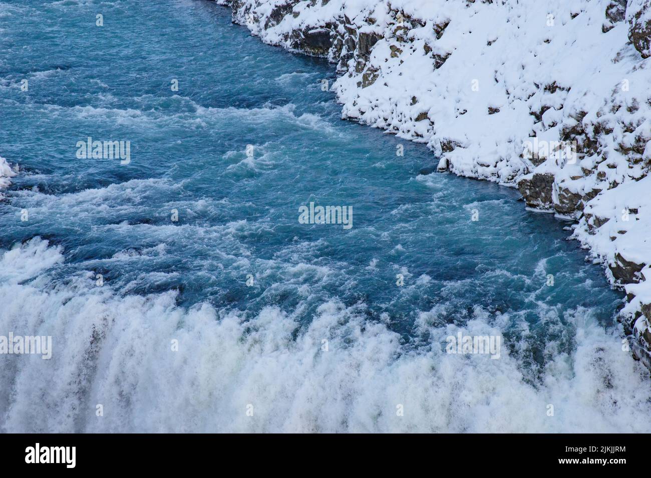 A natural view of river rushing downstream and a snow-covered riverside ...