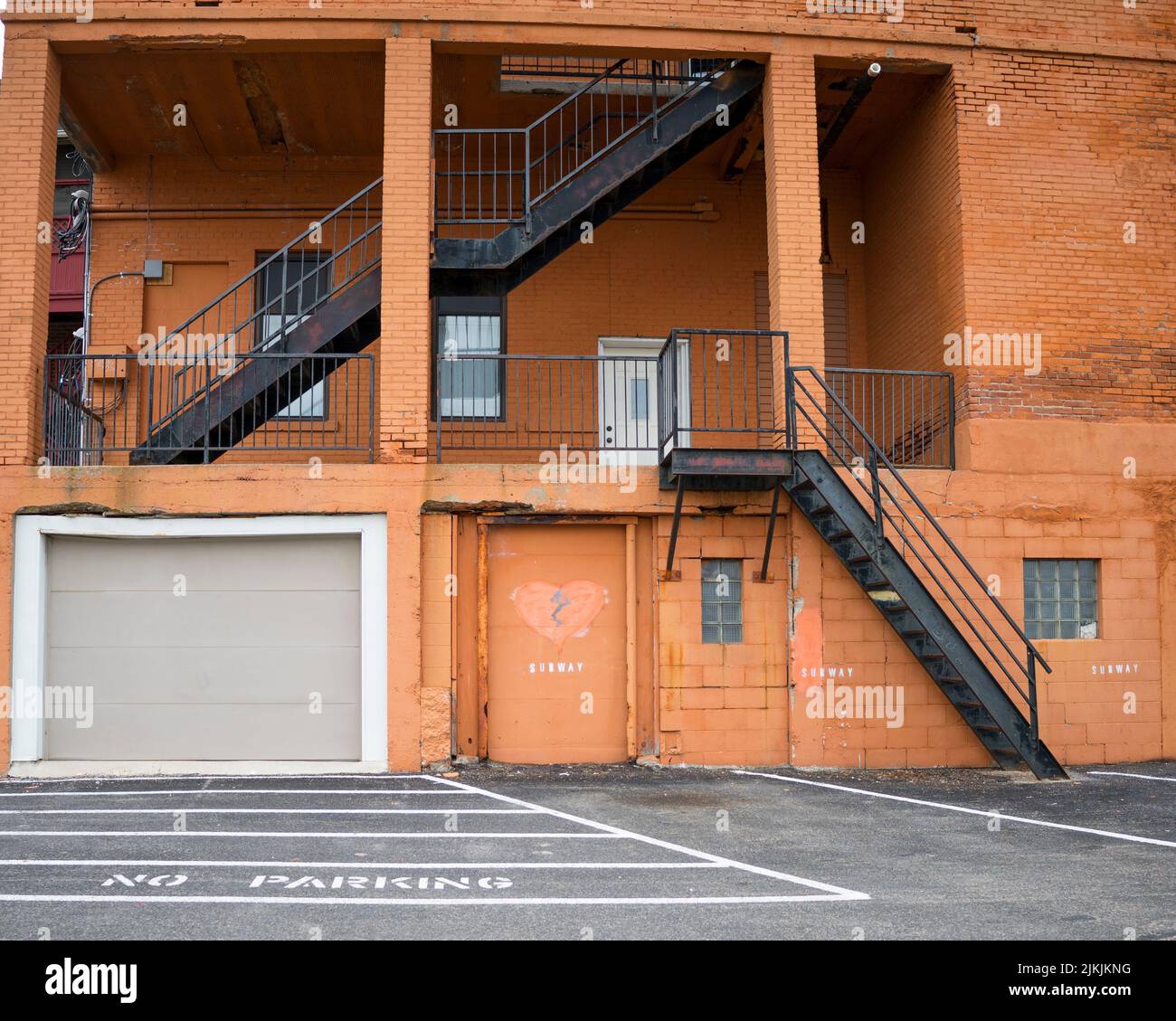 An orange brick wall building with black stairs Stock Photo - Alamy