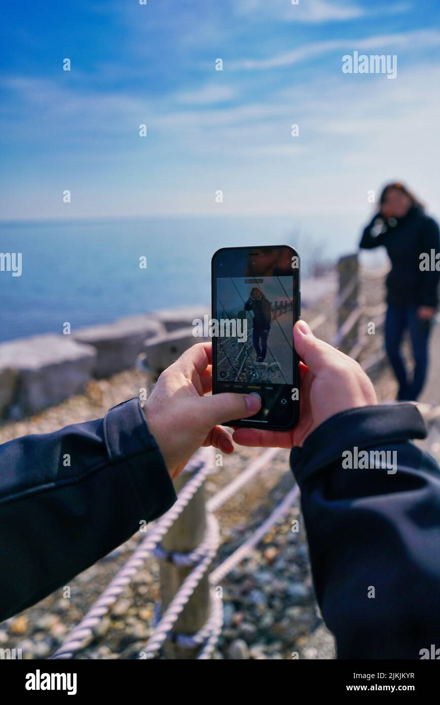 A vertical closeup shot of a husband taking portrait mode photos of his ...
