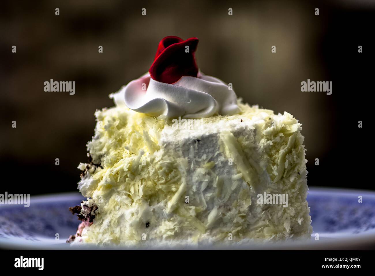 A shallow focus of a cake with white and red frosting swirl on top ...
