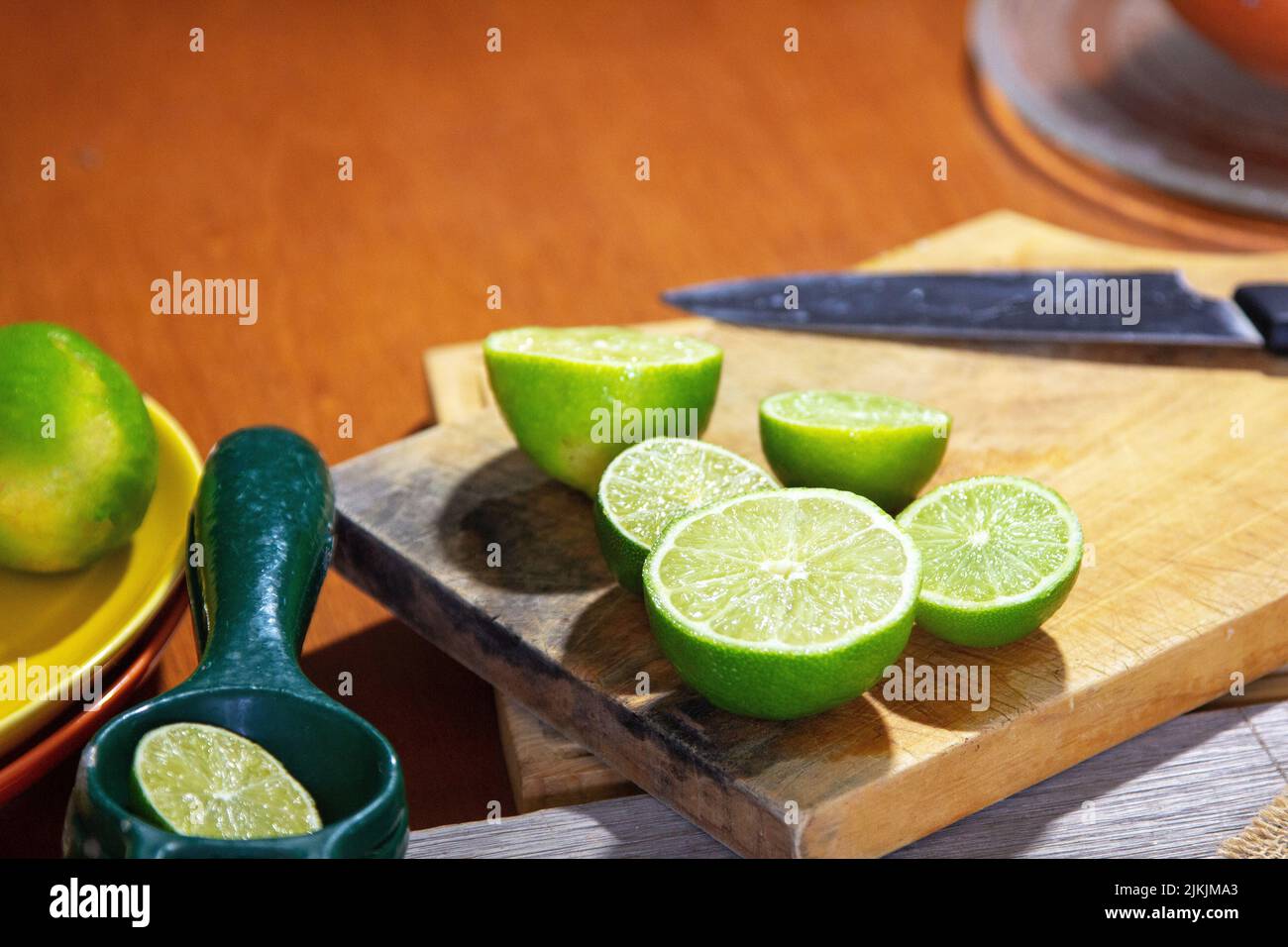A close-up shot of some sliced limes on a cutting board next to a sharp ...
