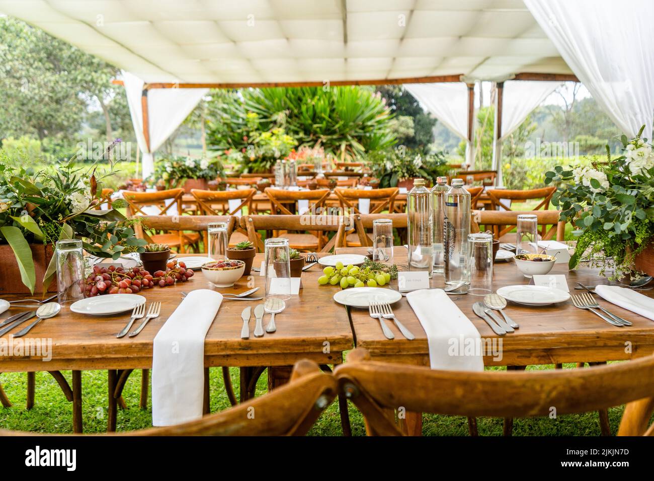 An outdoor dinner party venue with arranged wooden tables Stock Photo ...