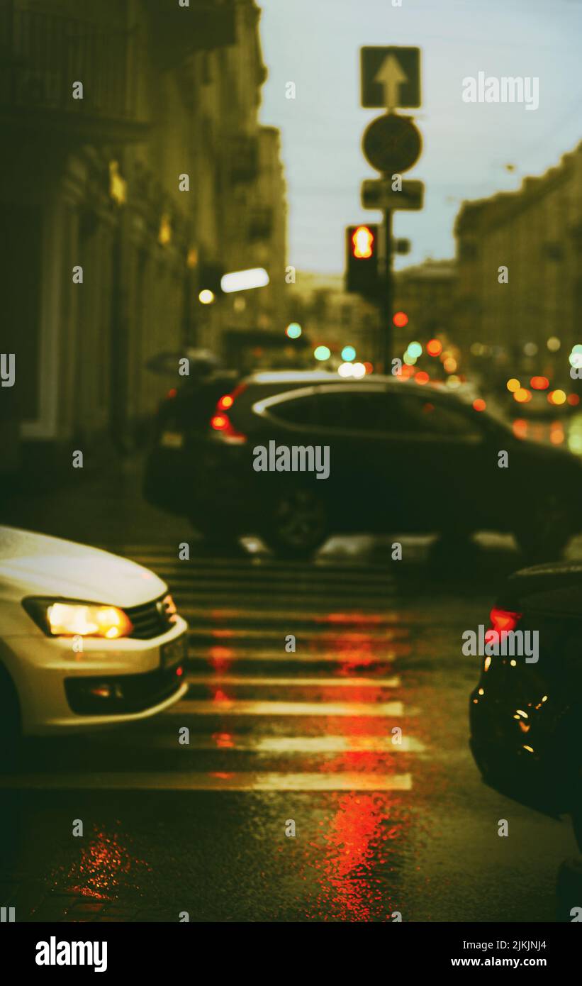 A vertical image of cars driving down the street of a rainy city at ...