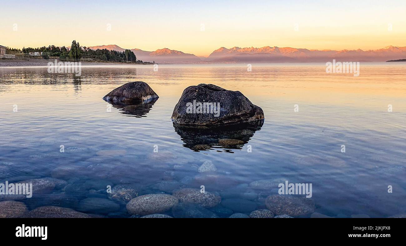 A scenic shot of two rocks submerged partly in crystal clear water ...