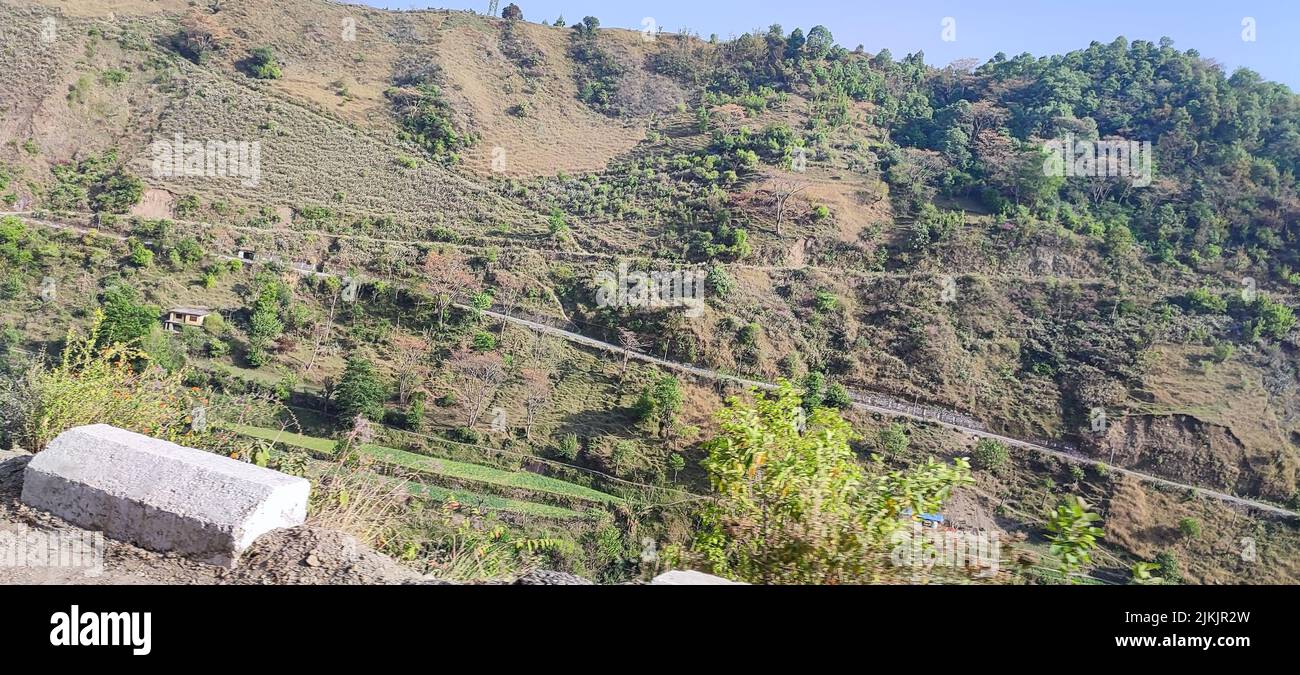 A shot of road passing over the mountain slope covered with vegetation ...