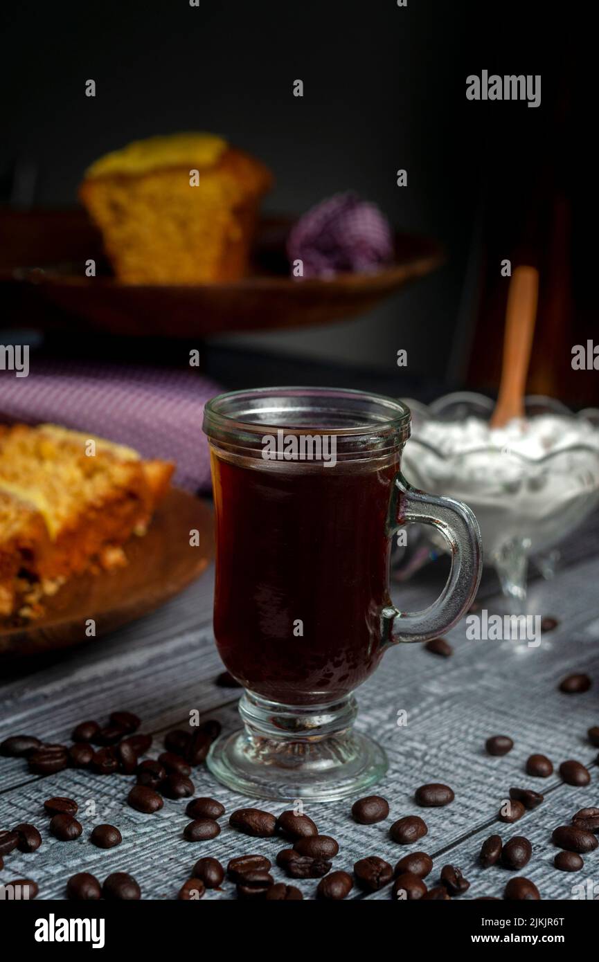A vertical shot of a cup of coffee with some coffee beans on the table ...