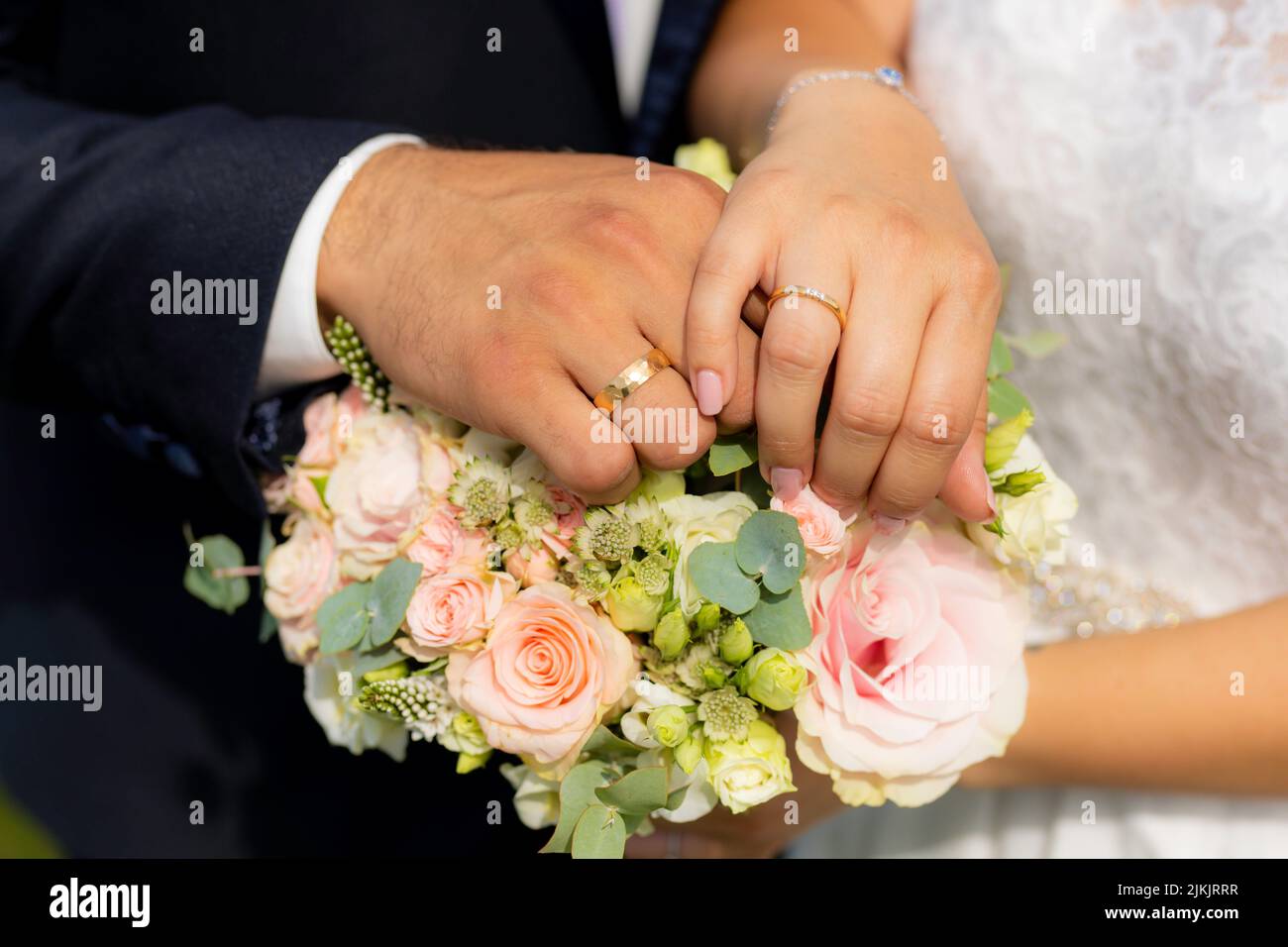 A closeup shot of the bride and groom hands wearing wedding bands on a ...