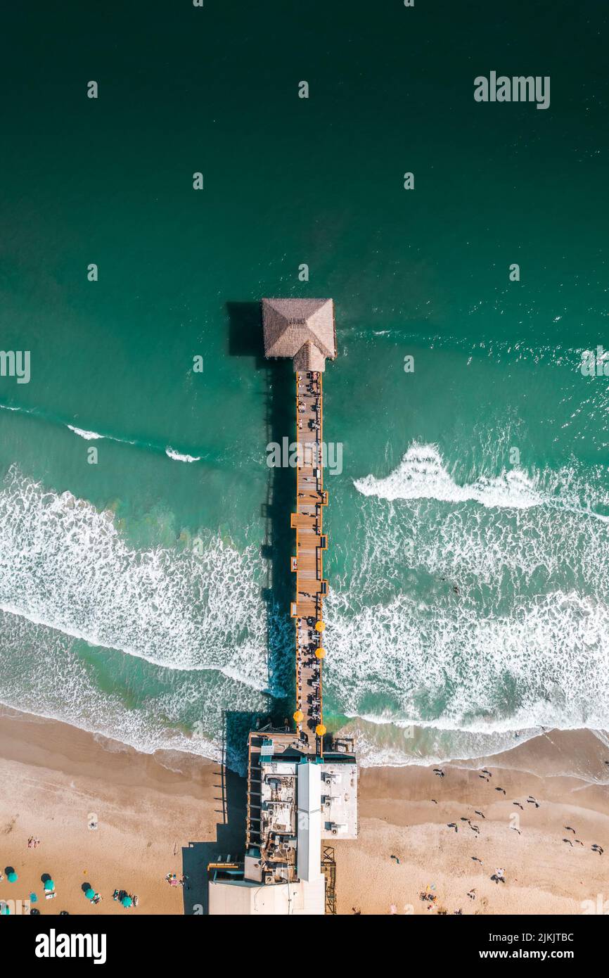 An aerial view of Cocoa beach and a pier with waves reaching to the ...