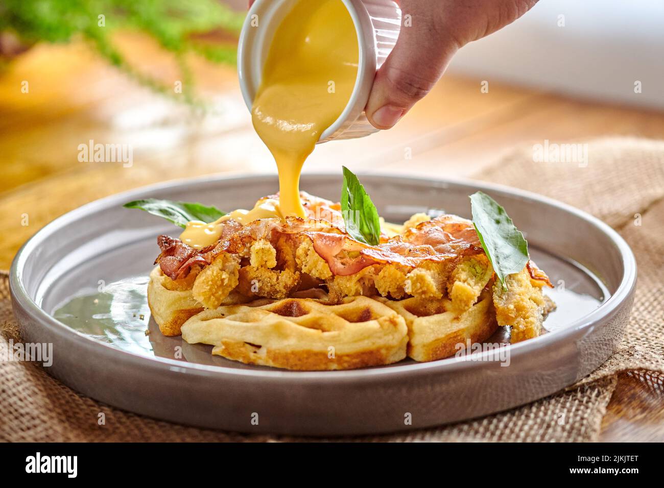 Waffle with melted cheese and bacon in a circular grey ceramic plate ...