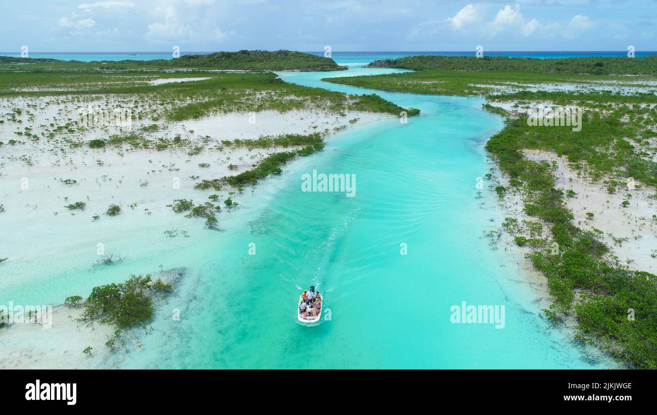 An aerial view of people sailing down a river in a white tiny boat at ...