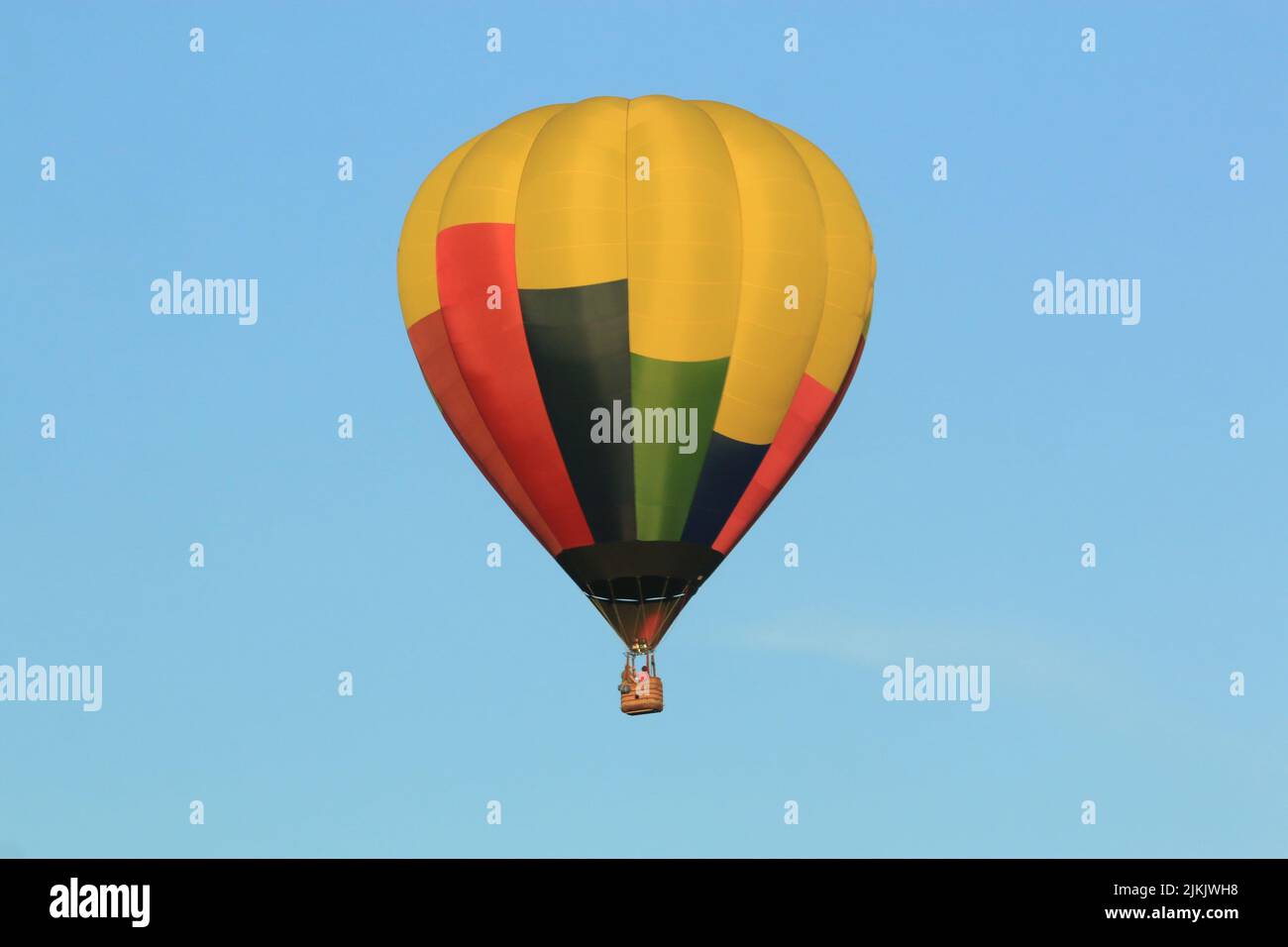 A closeup of a colorful hot air balloon flying in a cloudless blue sky Stock Photo - Alamy