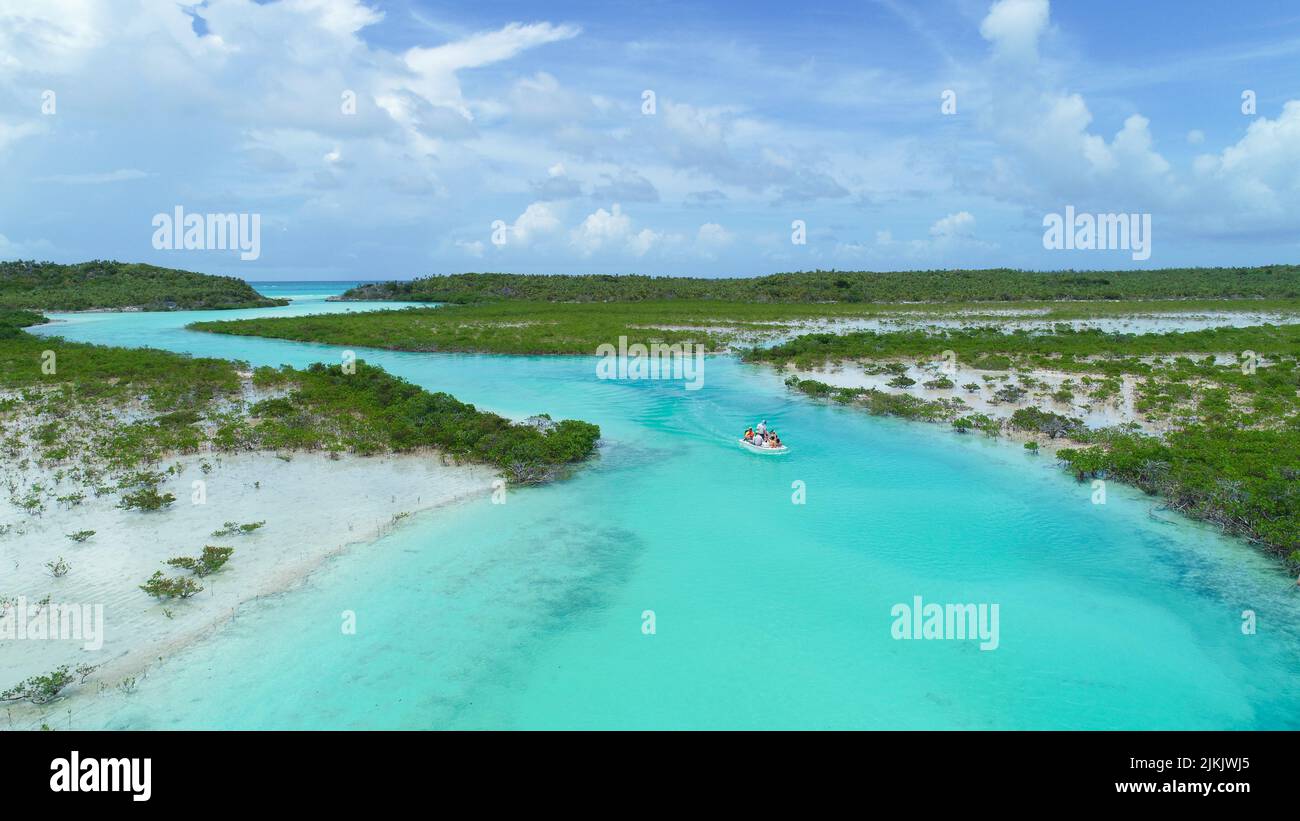 An aerial view of people sailing down a river in a white tiny boat at ...