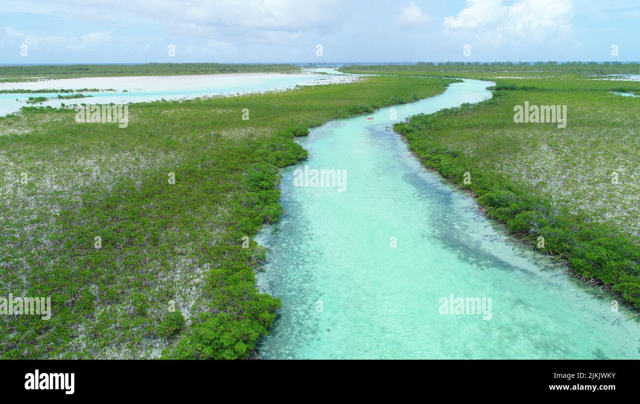 An aerial view of people sailing down a river in a white tiny boat at ...