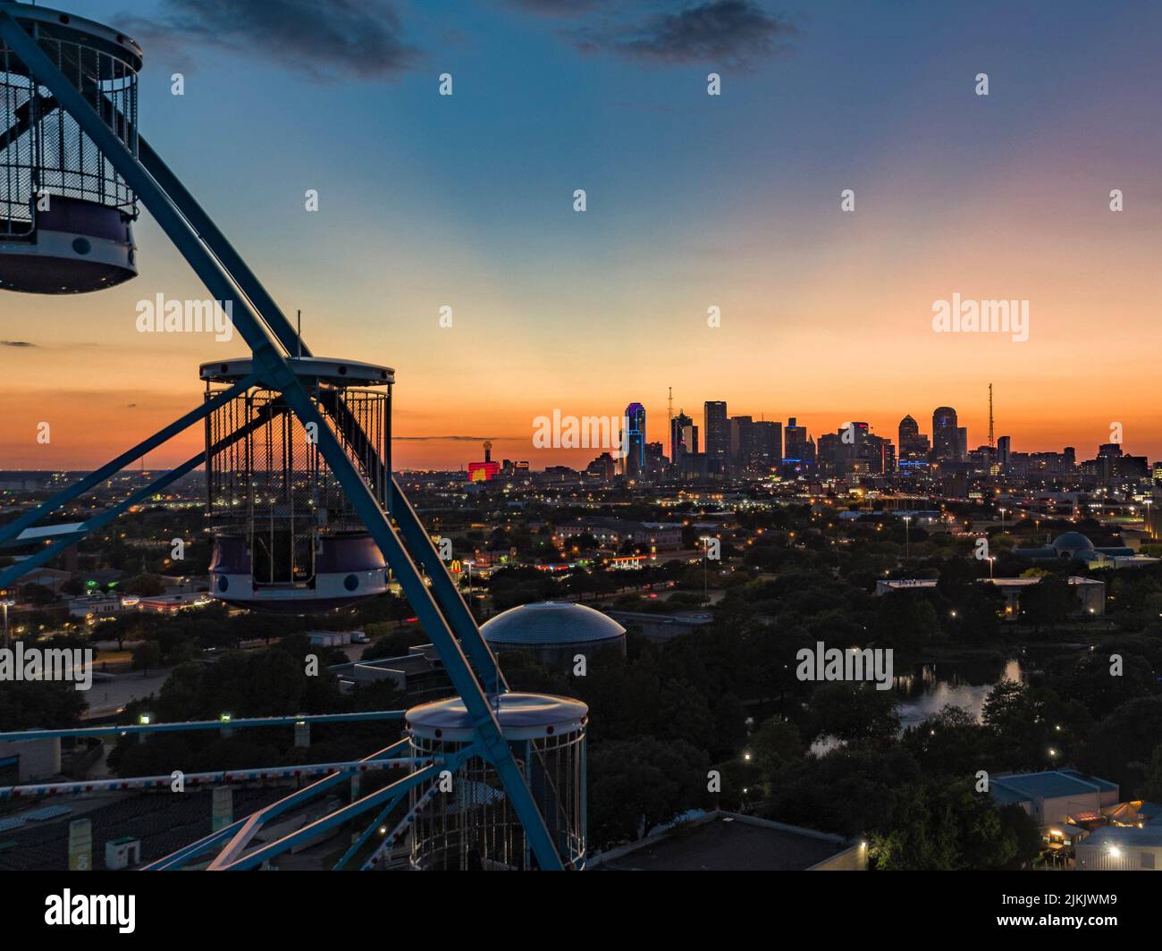 A scenic skyline with skyscrapers during sunset shot of a ferris wheel ...