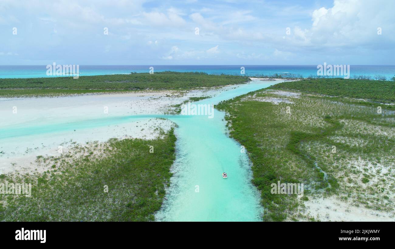 An aerial view of people sailing down a river in a white tiny boat at ...