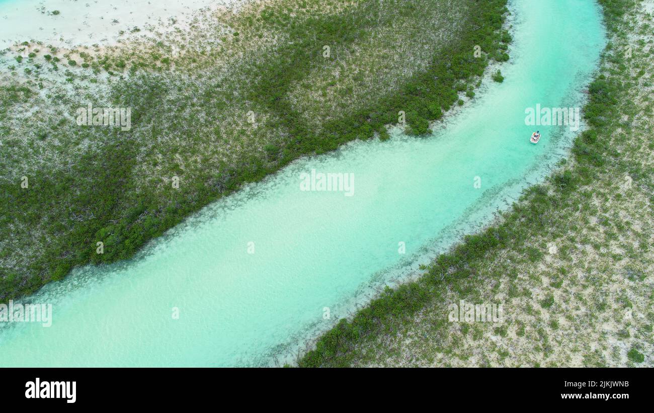 An aerial view of people sailing down a river in a white tiny boat at ...