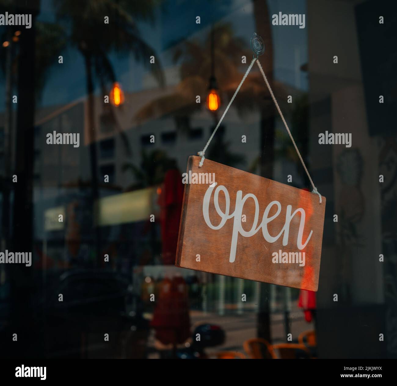 A wooden "Open" sign hanging on the glass door of a store Stock Photo ...