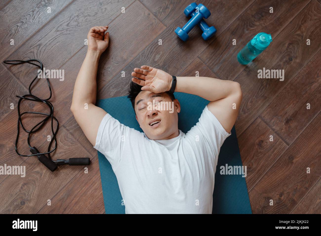Fatigue after exercising at home. Tired mature asian man wiping sweat ...