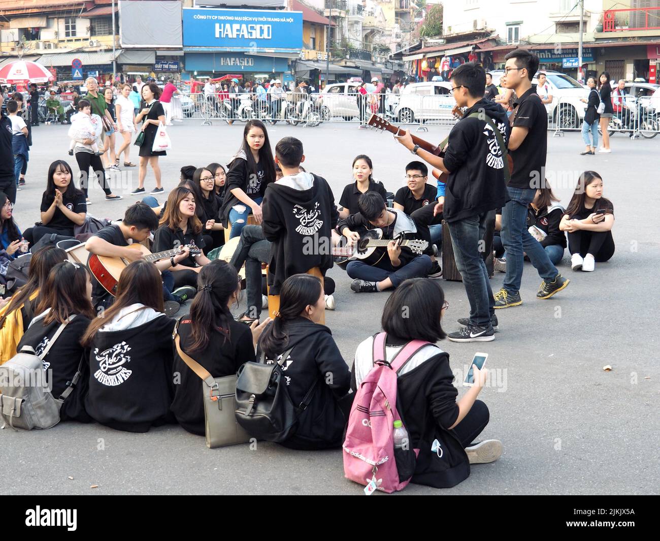 A group of teens dressed in black and listening to a music duo on a ...
