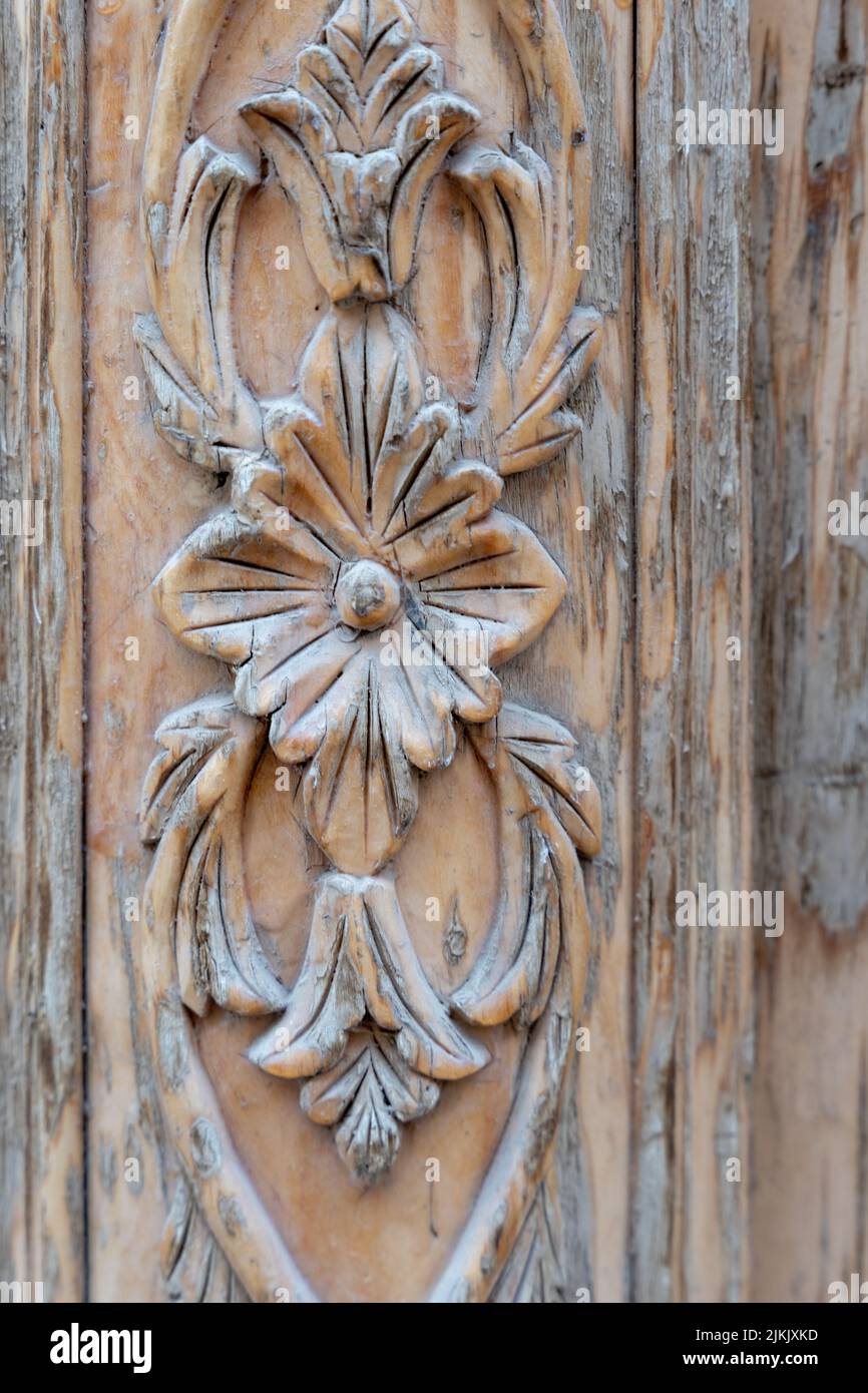 A vertical shot of an old carved wood with the bas-relief ornament ...