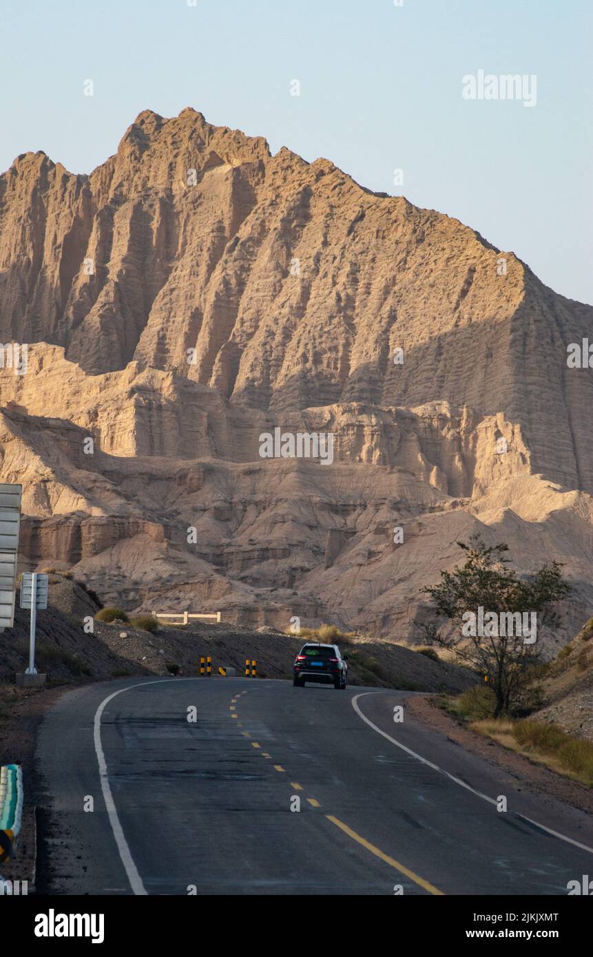 A vertical shot of a highway on a background of a cliff in daylight ...
