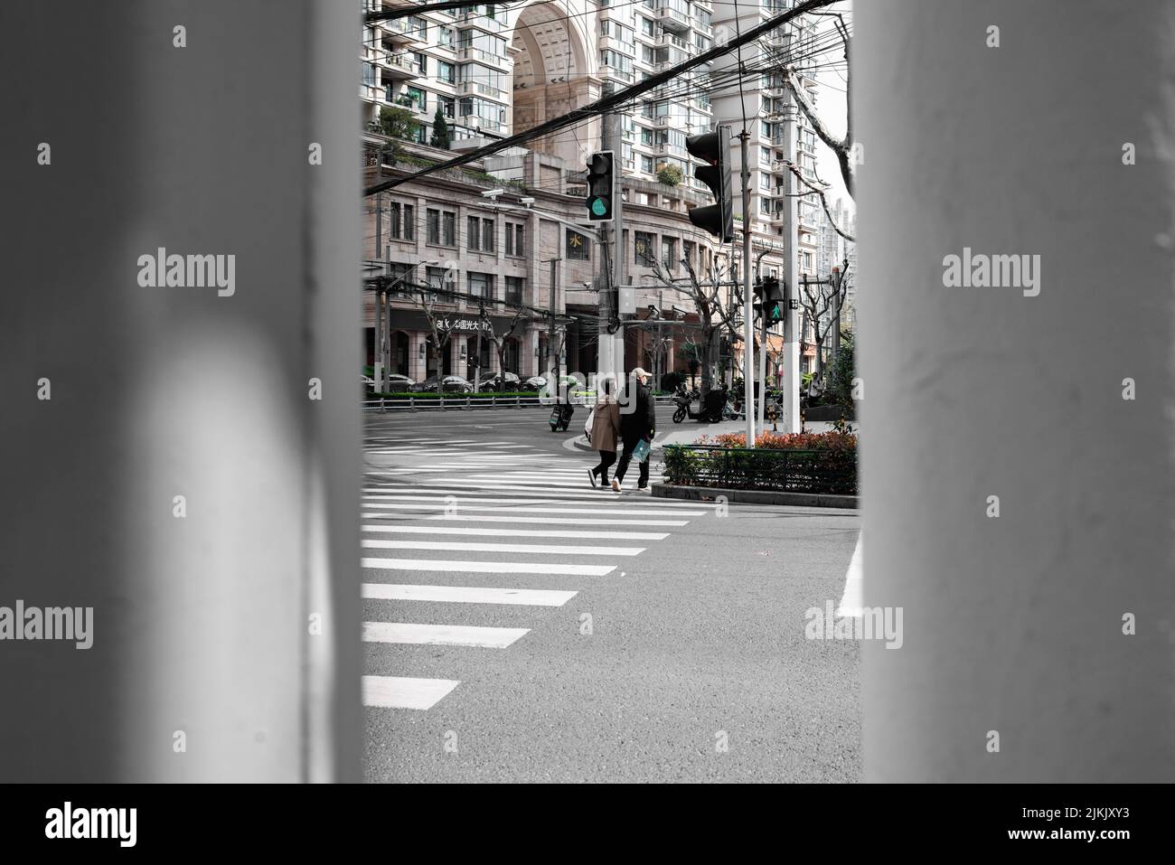 A back view of a young couple passing the pedestrian crossing in ...