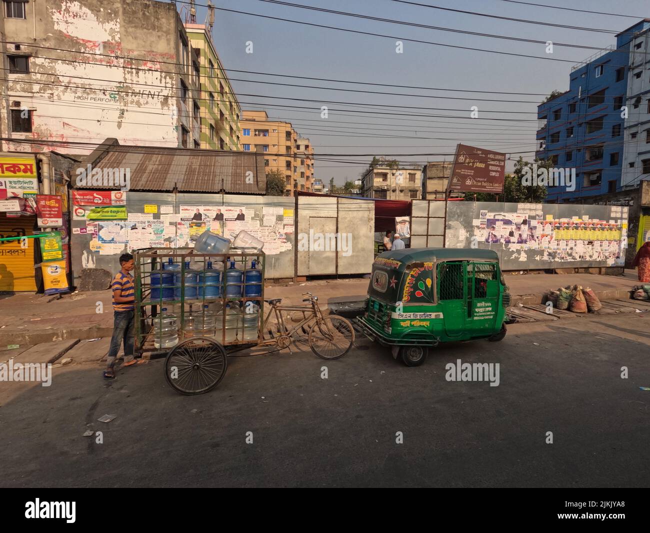 A male with his water delivery cart beside a public transport vehicle ...