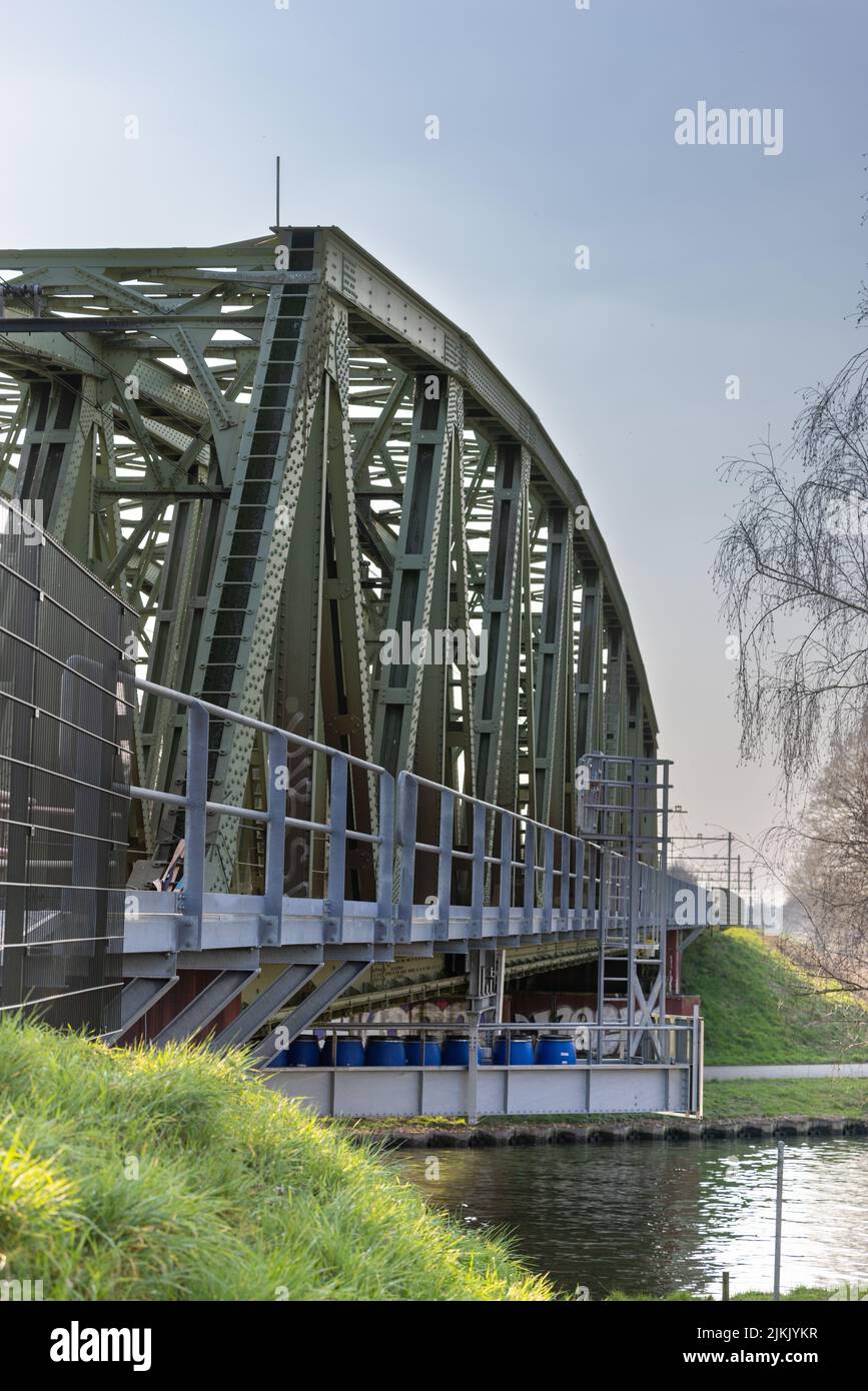 A vertical shot of a train bridge over a river in the Netherlands going ...